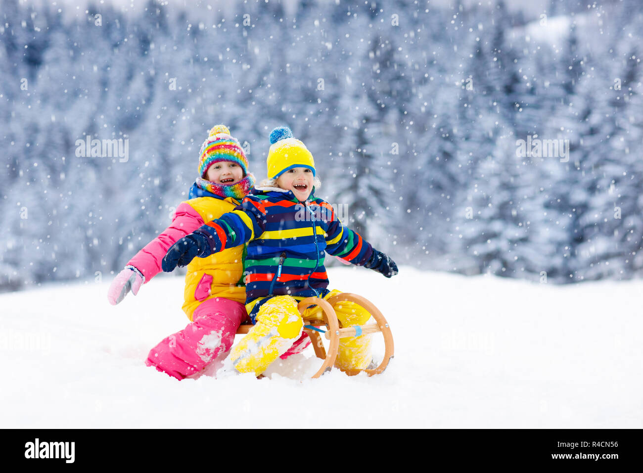 Little girl and boy enjoying sleigh ride. Child sledding. Toddler kid ...