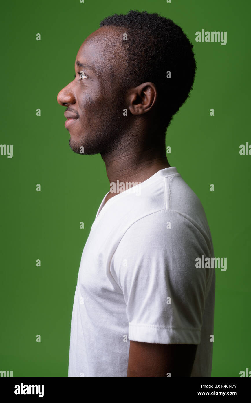 Profile view portrait of young African man against green background ...