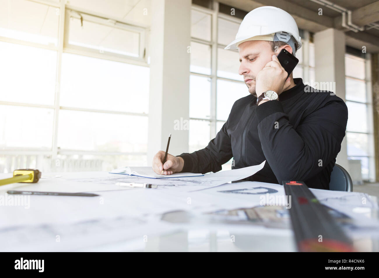 architect builder works at the table with drawings. Helmet, drawings ...