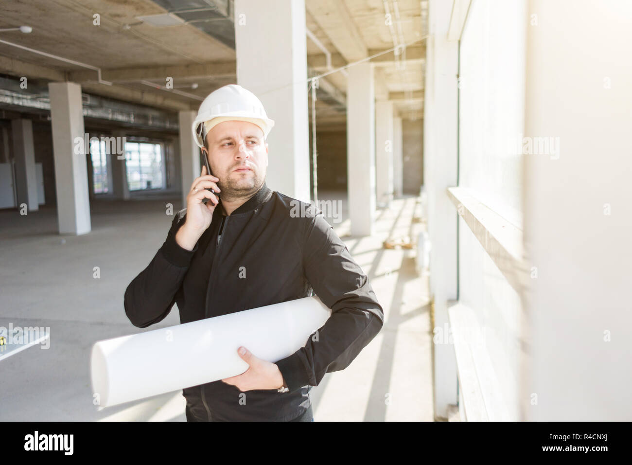 the builder architect in a helmet with drawings is working at the ...