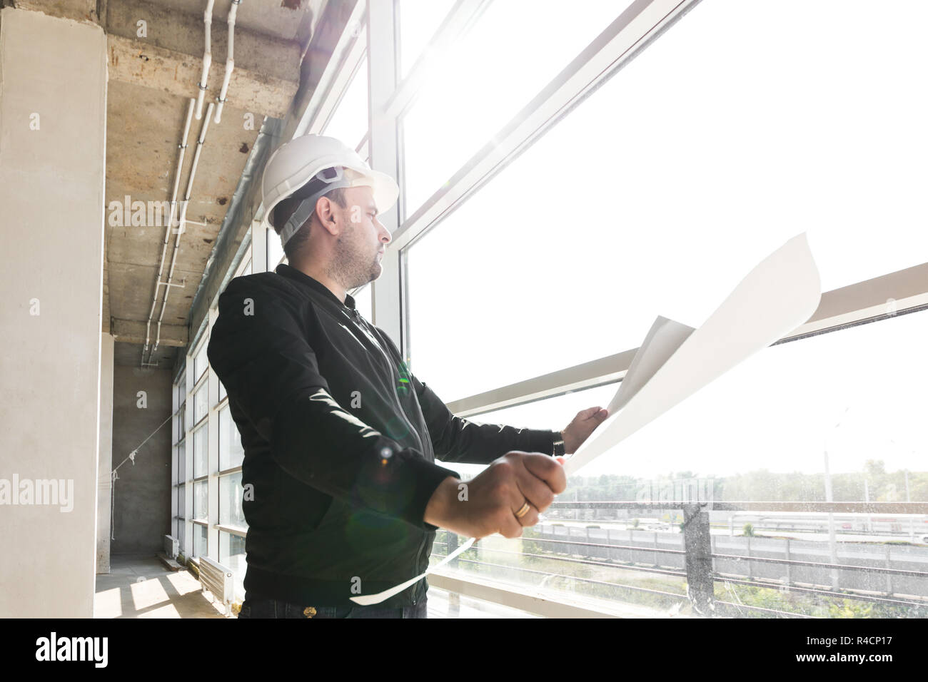 the builder architect in a helmet with drawings is working at the ...