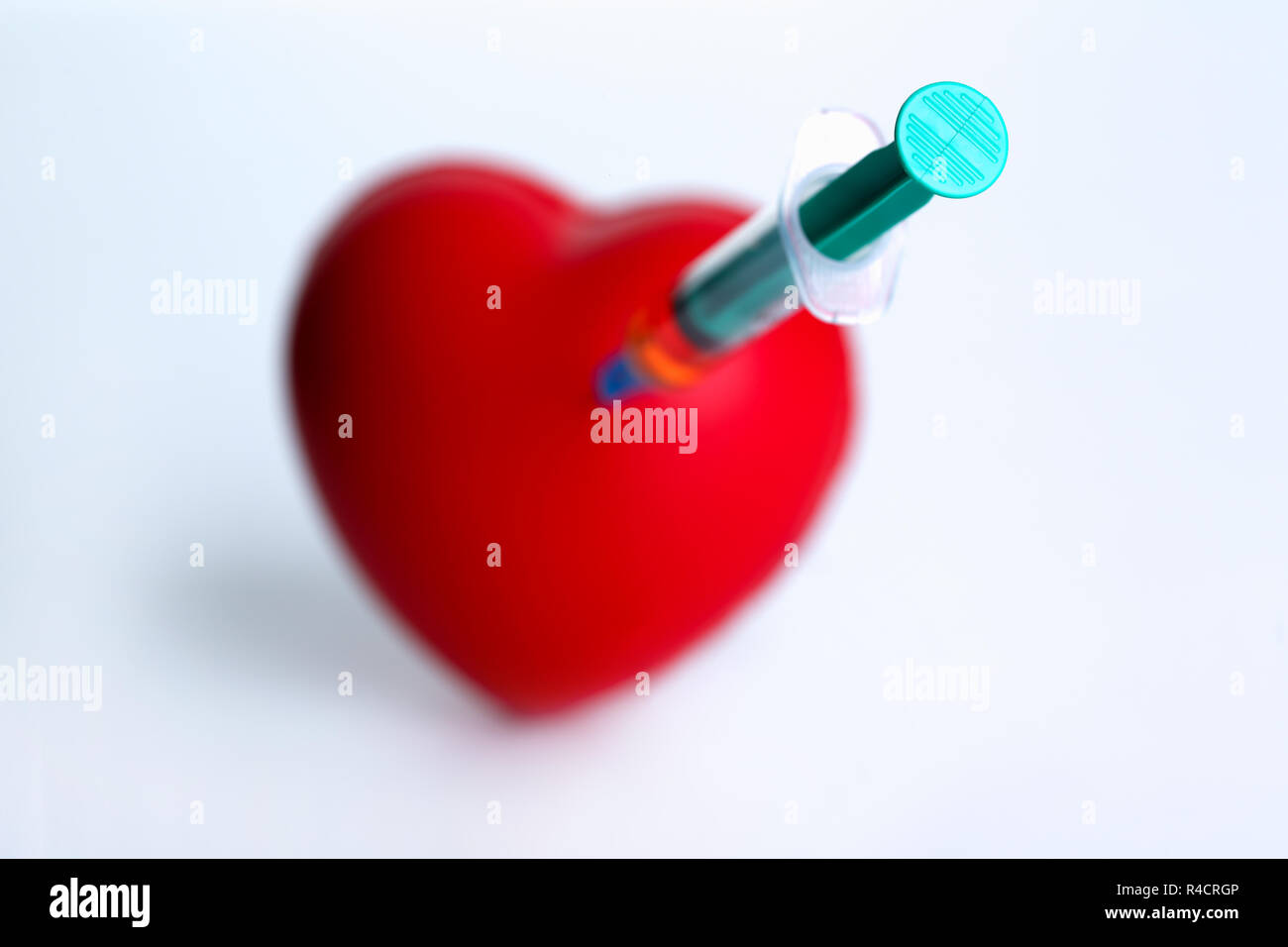 Red heart with stuck syringe on gray background Stock Photo - Alamy