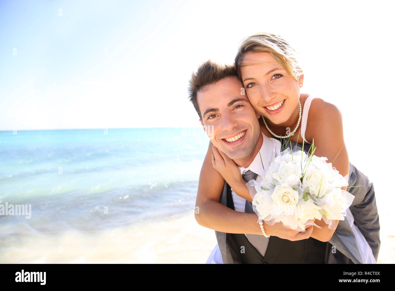 Groom giving piggyback ride to his bride Stock Photo - Alamy