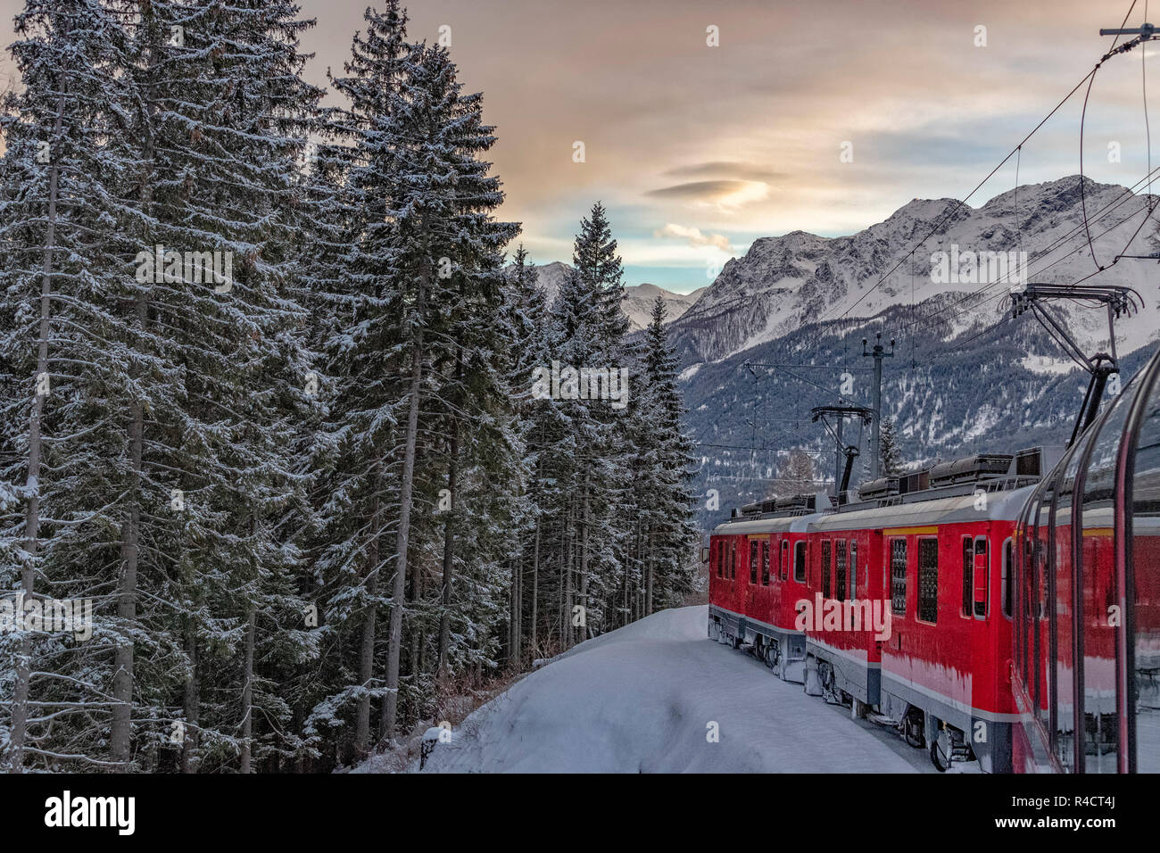 Red train running in the snow in swiss alps in winter Stock Photo - Alamy