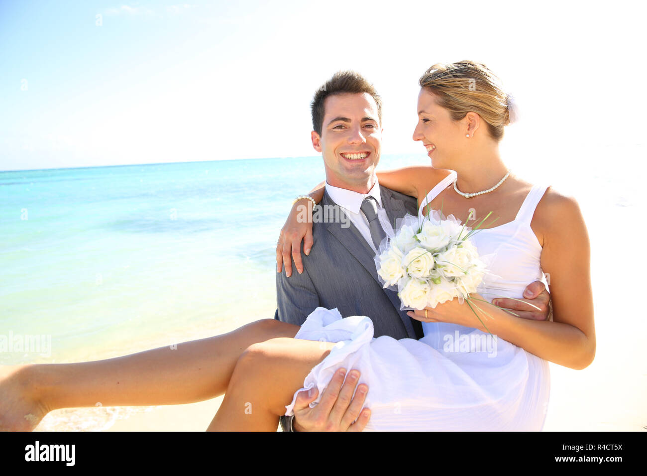 Happy groom holding bride in his arms Stock Photo - Alamy