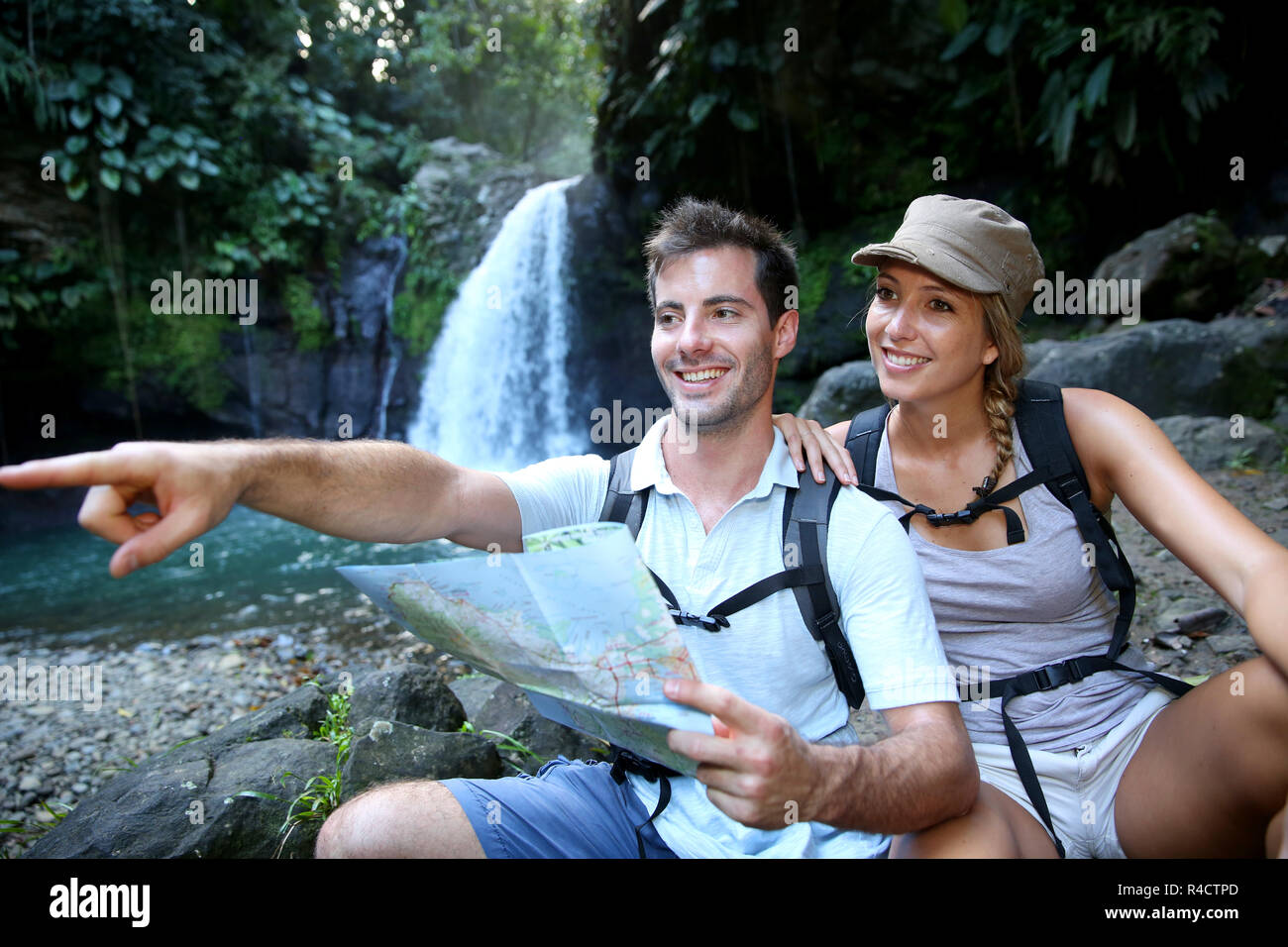 Hikers looking at map by waterfall Stock Photo - Alamy
