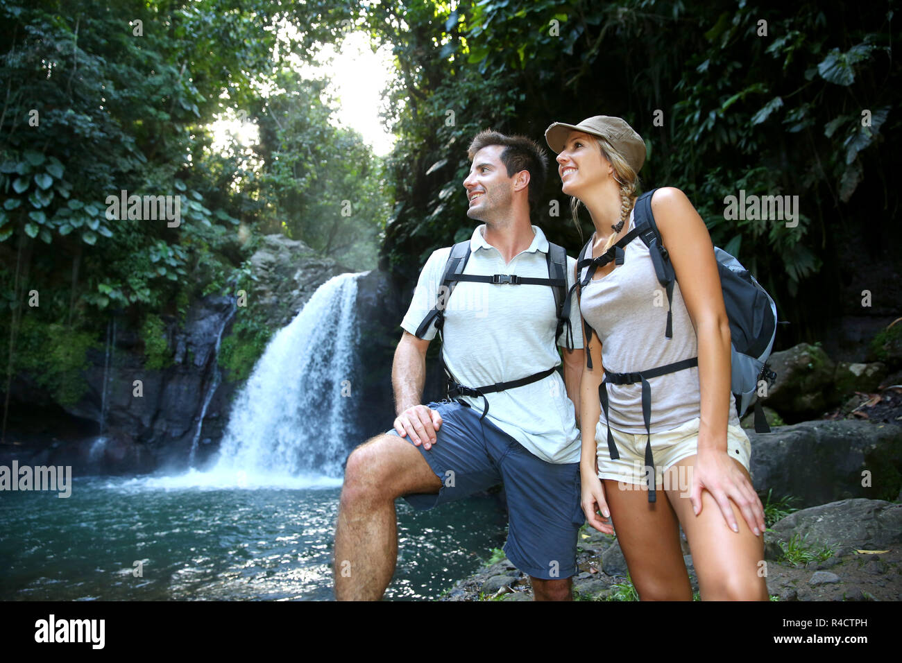 Trekkers reaching waterfall in natural landscape Stock Photo - Alamy