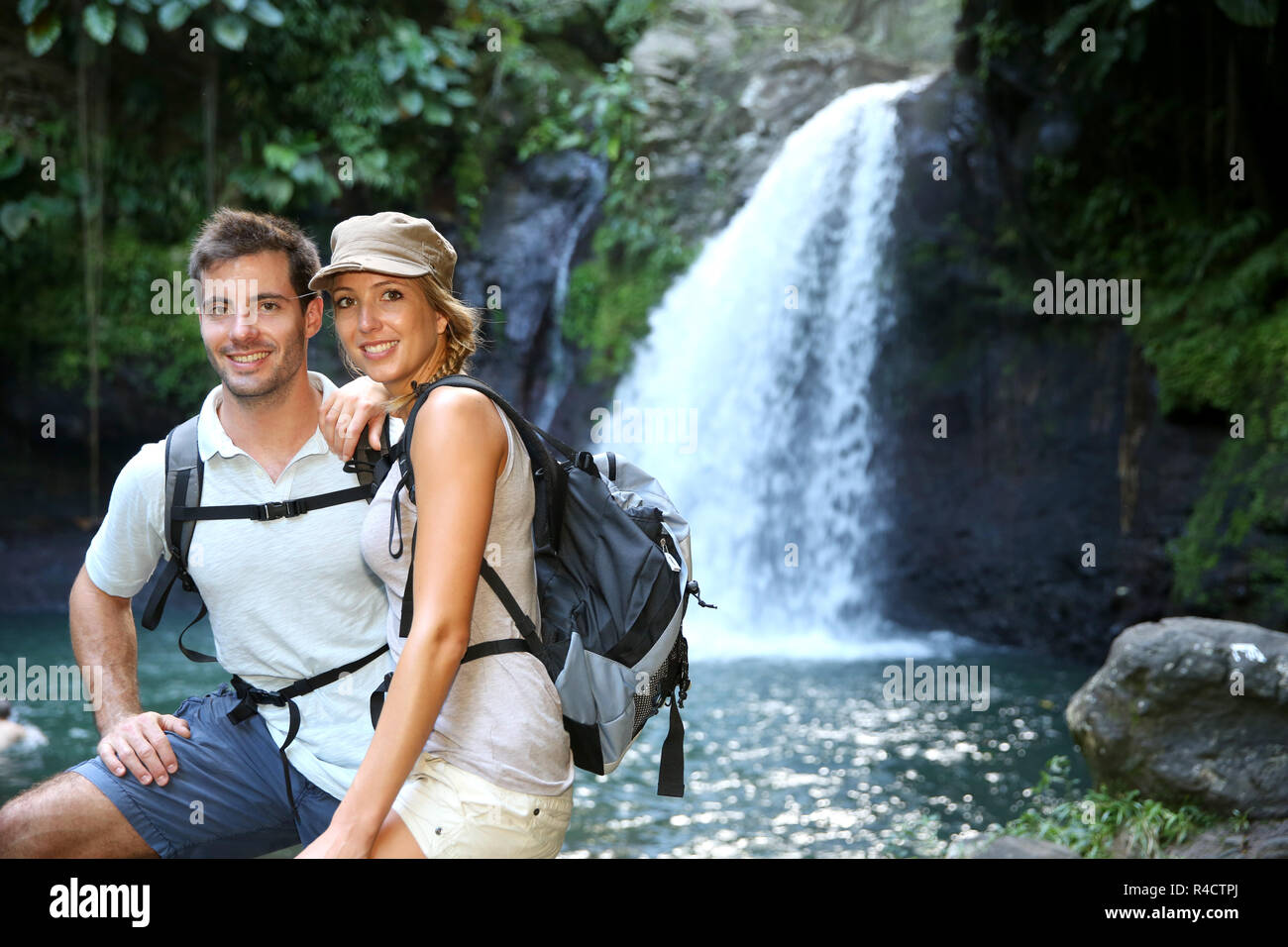 Trekkers reaching waterfall in natural landscape Stock Photo - Alamy