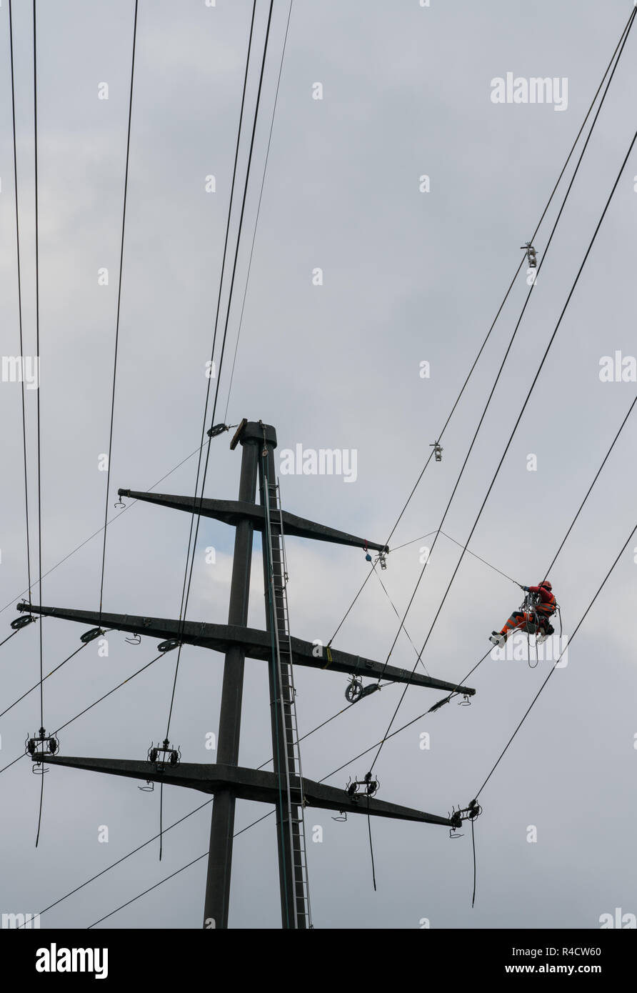 Working professional men on high voltage power lines high up on lattice ...