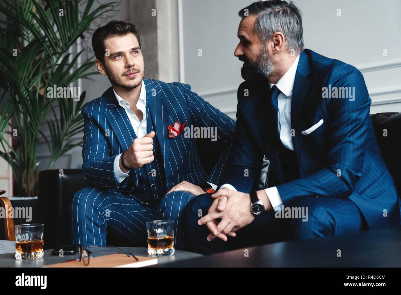 Relaxing. Full length of two young handsome men in suits holding ...