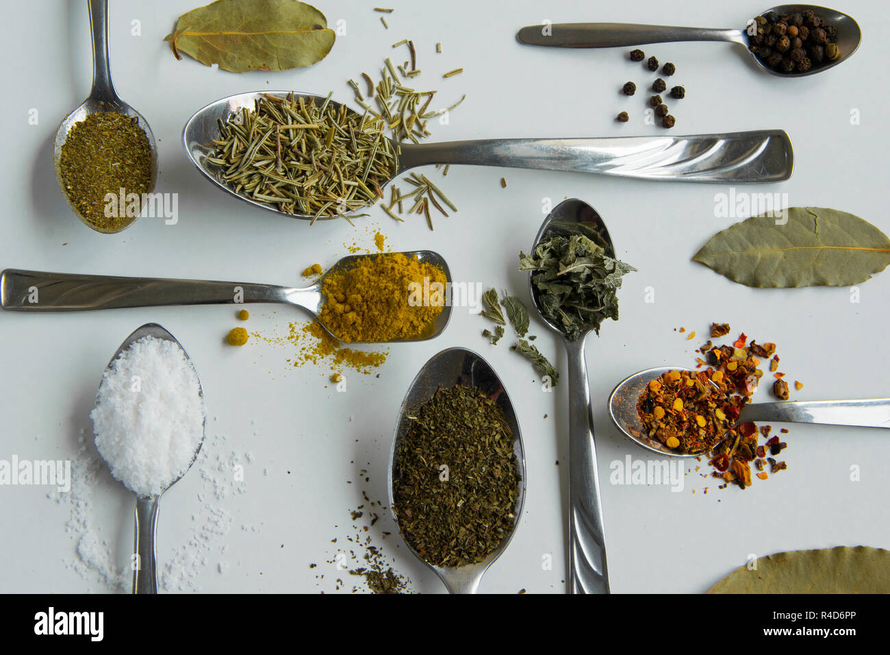 Top view of spoons with various aromatic herbs and spices on white ...