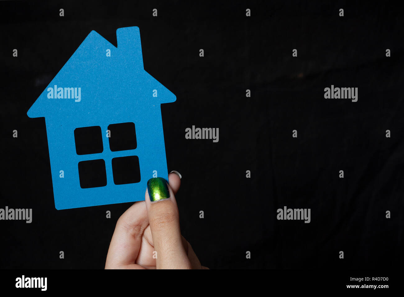 hand holding a little blue paper house - black background Stock Photo ...