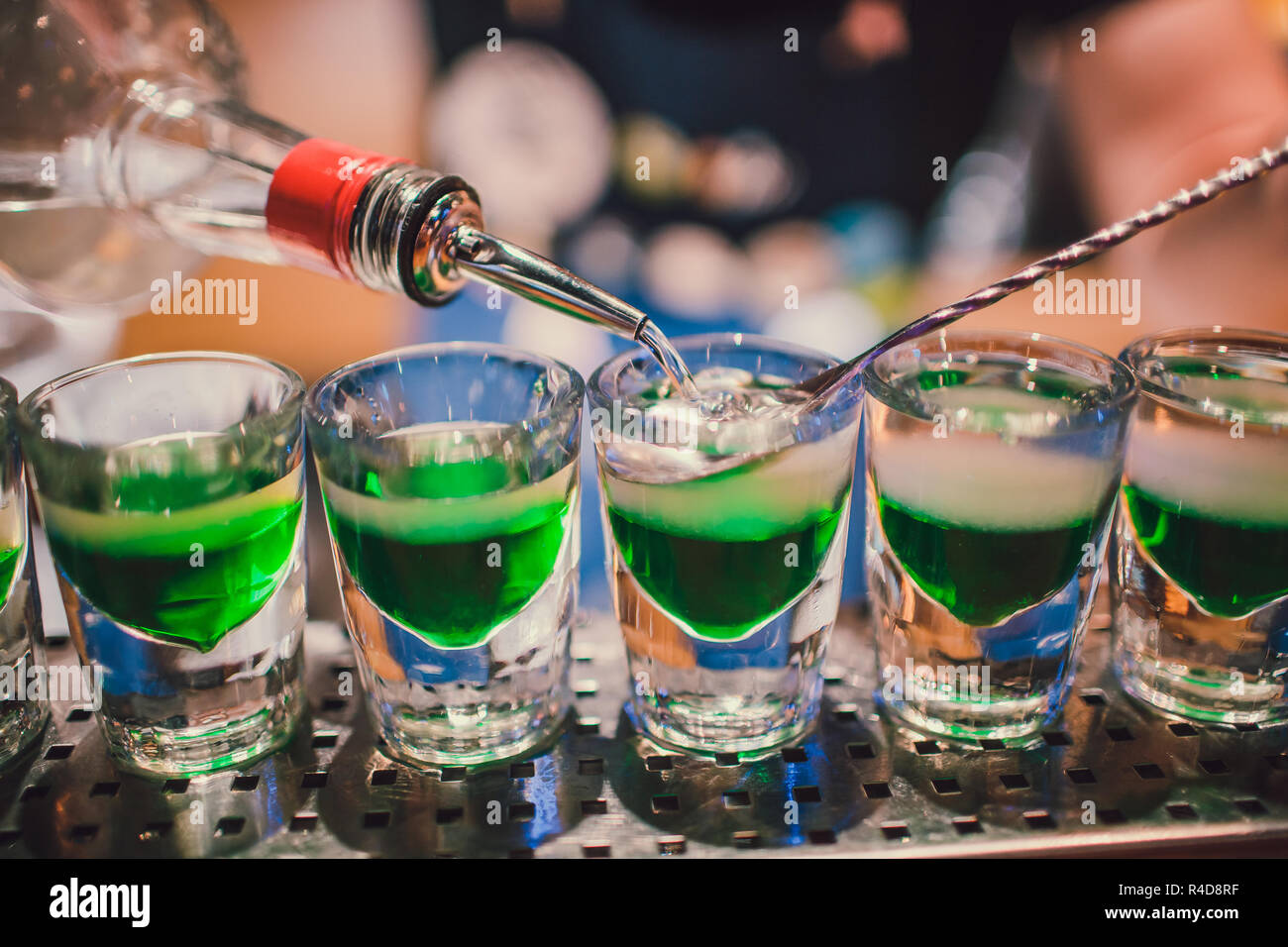 Green liquid in shot glasses standing on the counter. bartender ...