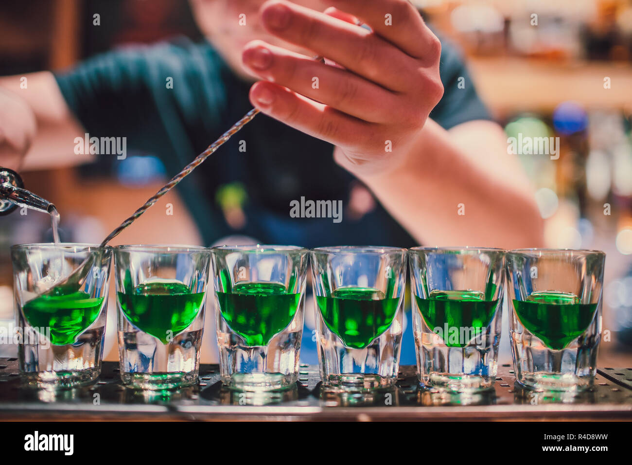 Green liquid in shot glasses standing on the counter. bartender ...