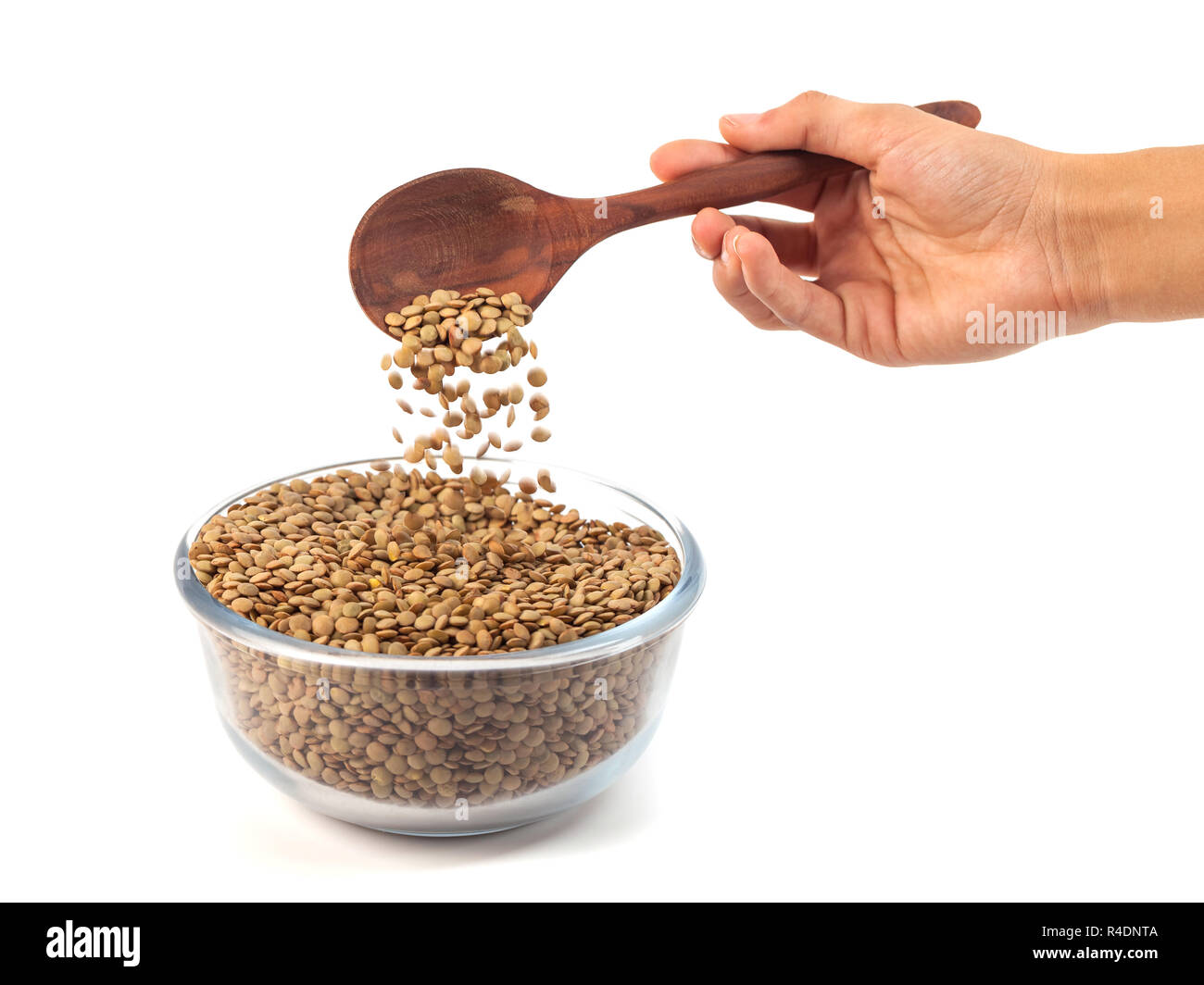 dry lentil in glass bowl with wooden spoon in the hand isolated on white background Stock Photo ...
