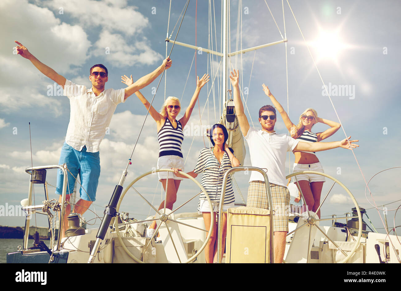 smiling friends sitting on yacht deck and greeting Stock Photo - Alamy