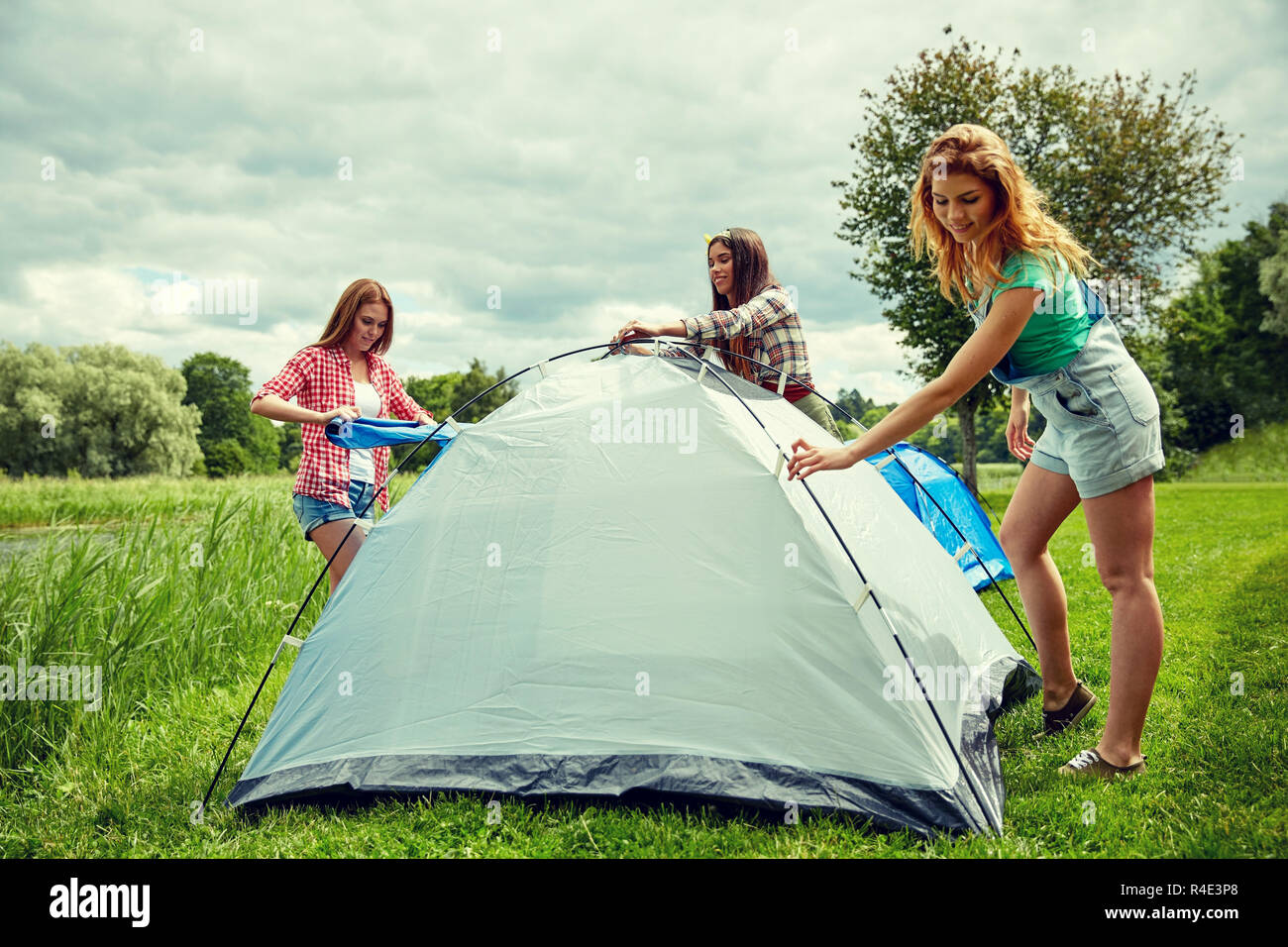 smiling friends setting up tent outdoors Stock Photo - Alamy