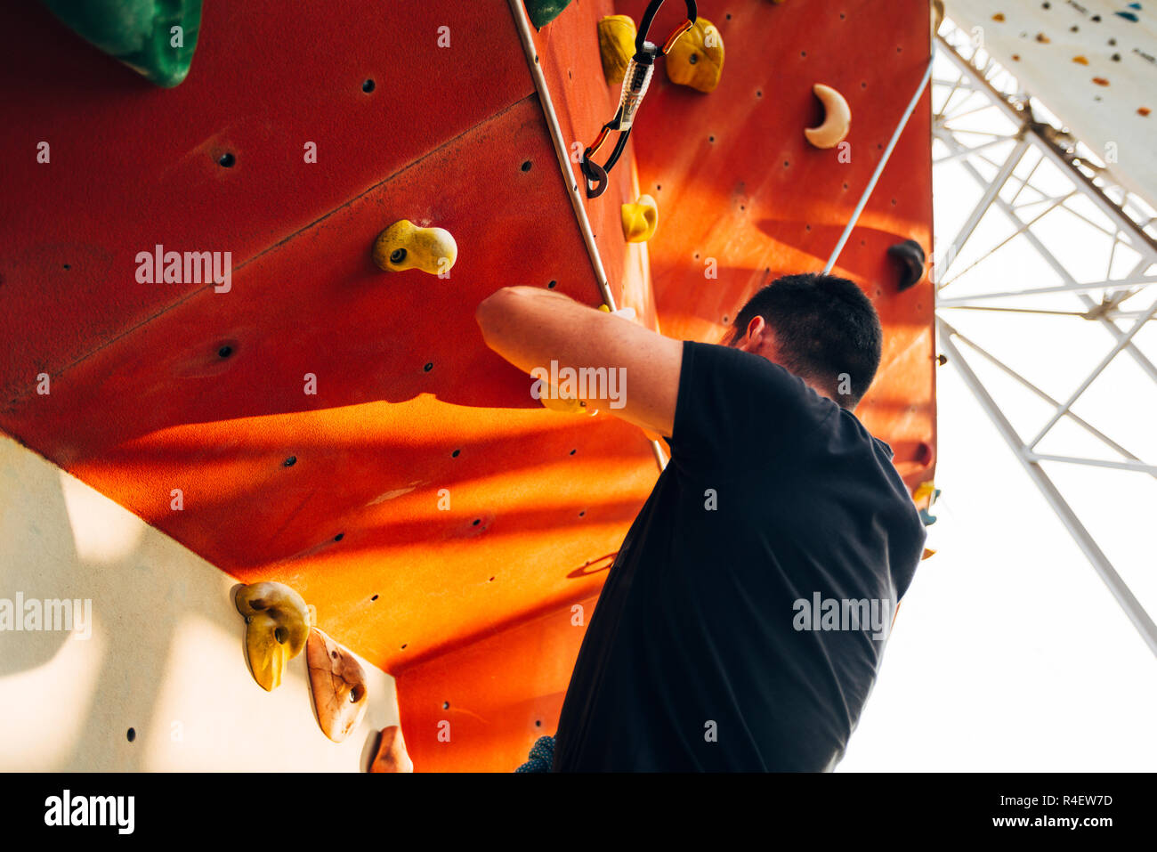 Young climber guy climbing on practical rock in climbing center ...