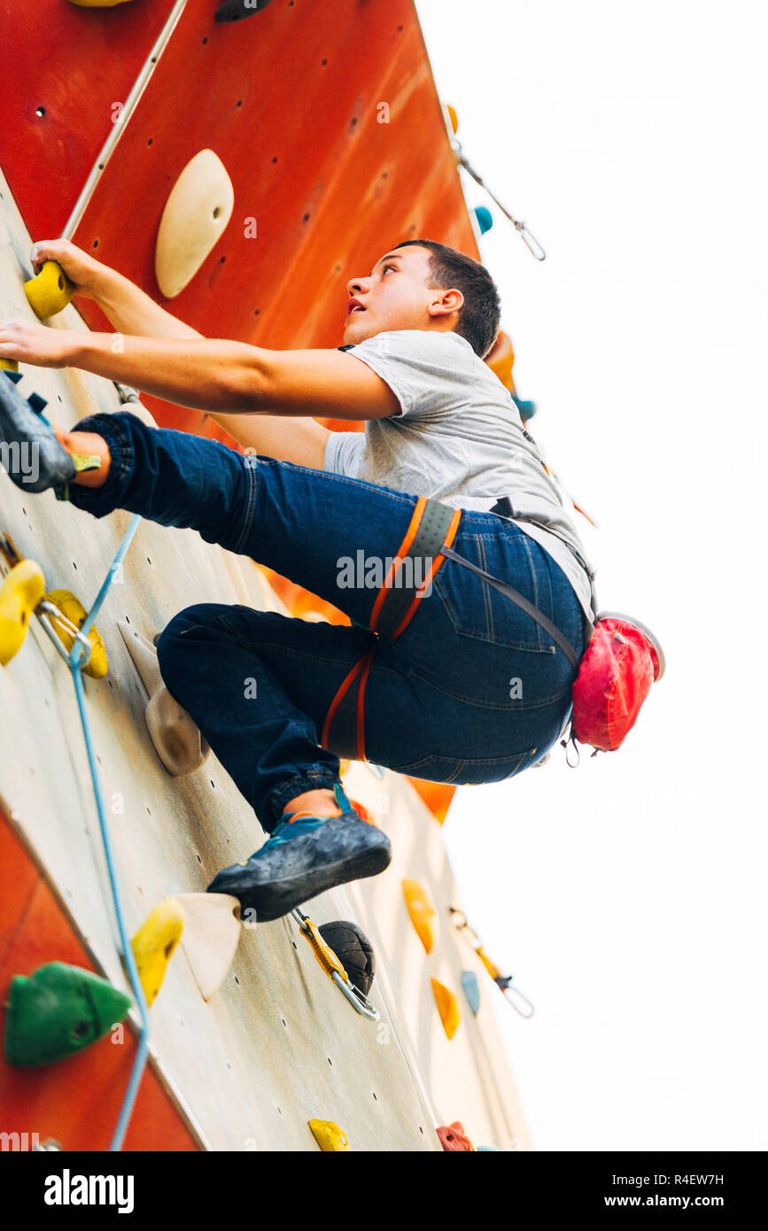 Young climber guy climbing on practical rock in climbing center ...
