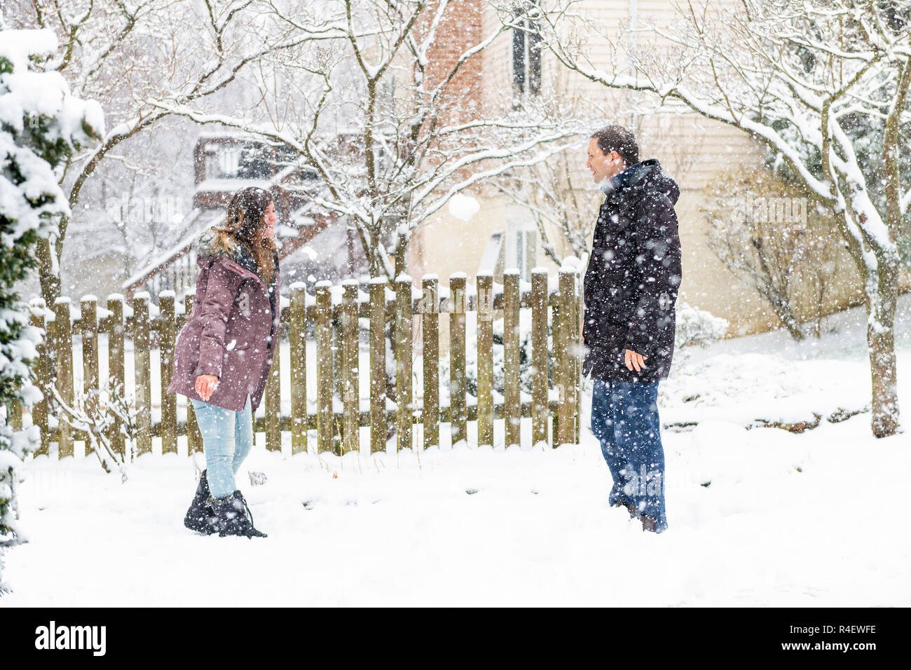 Young man, woman playing, standing, throwing flying snowballs in air ...