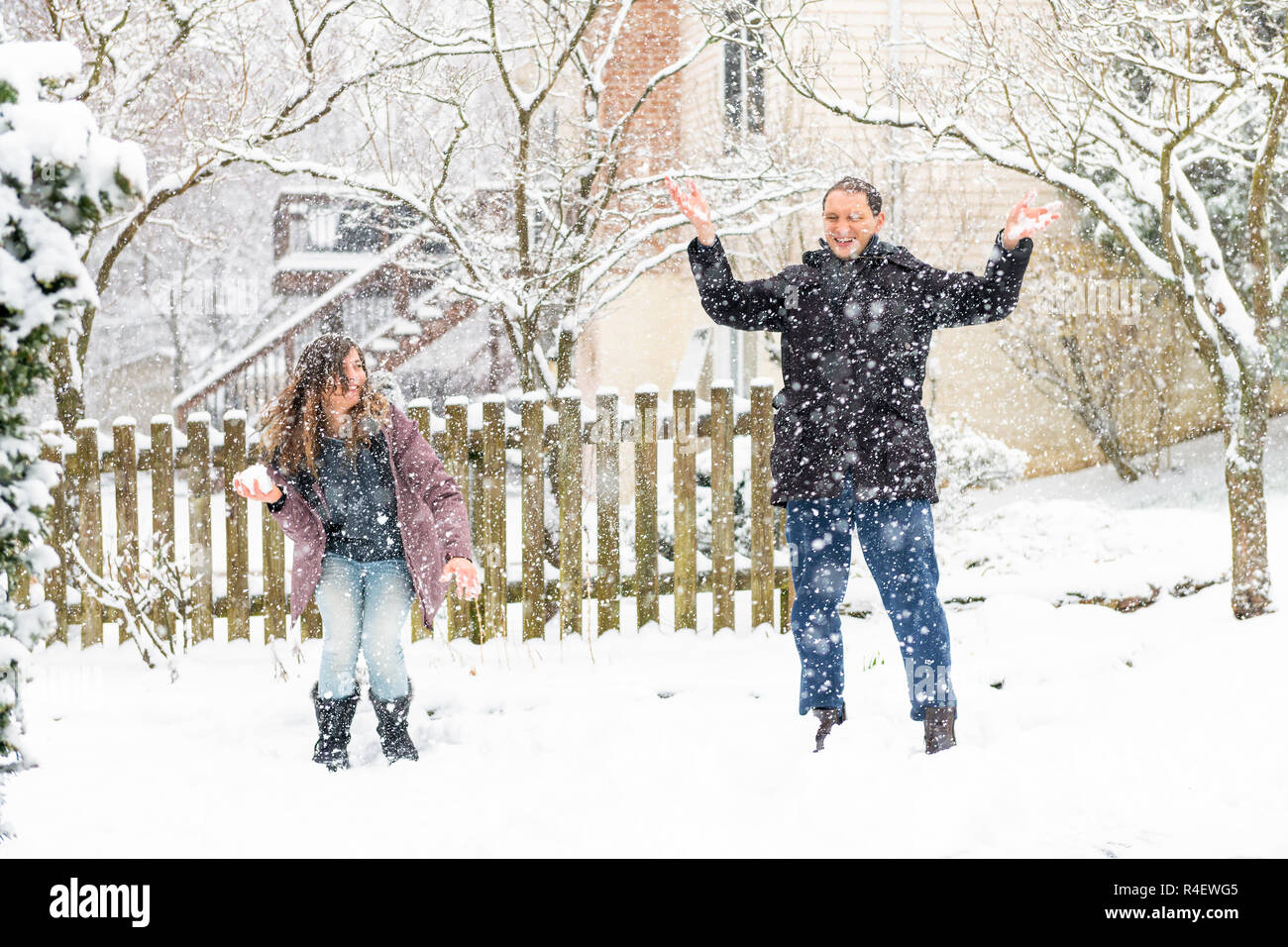 Young man, woman playing, throwing snowballs in winter snowstorm, storm ...