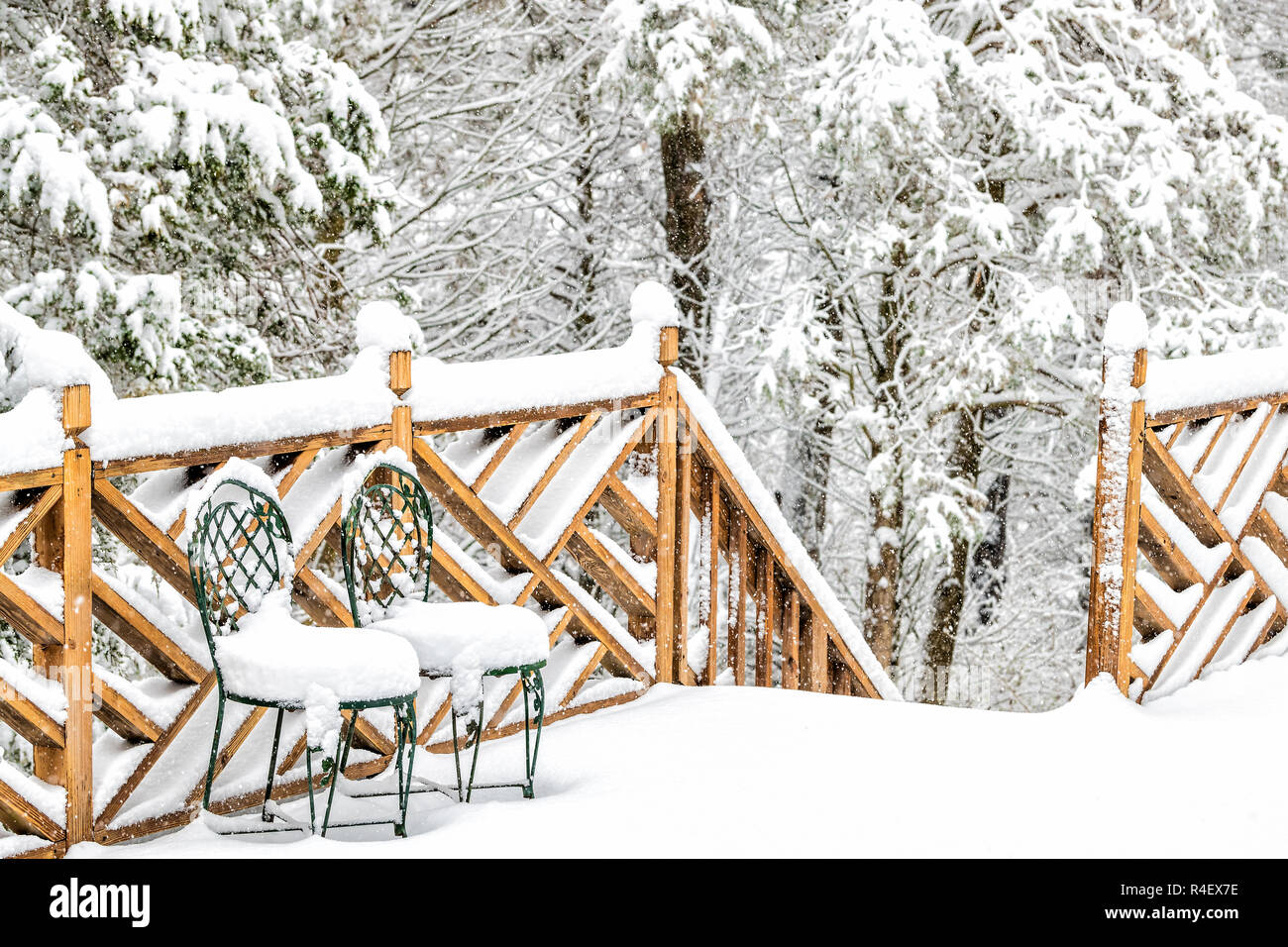 Snow covered house, home wooden deck with two cast iron chairs, snowing ...