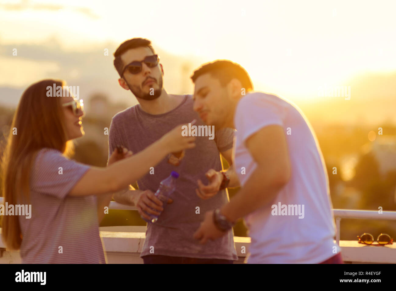 Group of cheerful friends having fun and eating chocolate on balcony ...