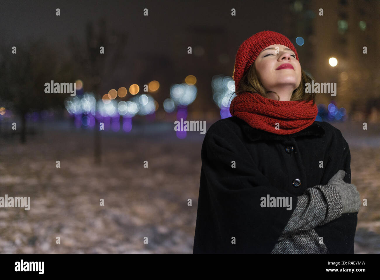 Red hat girl standing in front of Christmas tree lights at night Stock ...