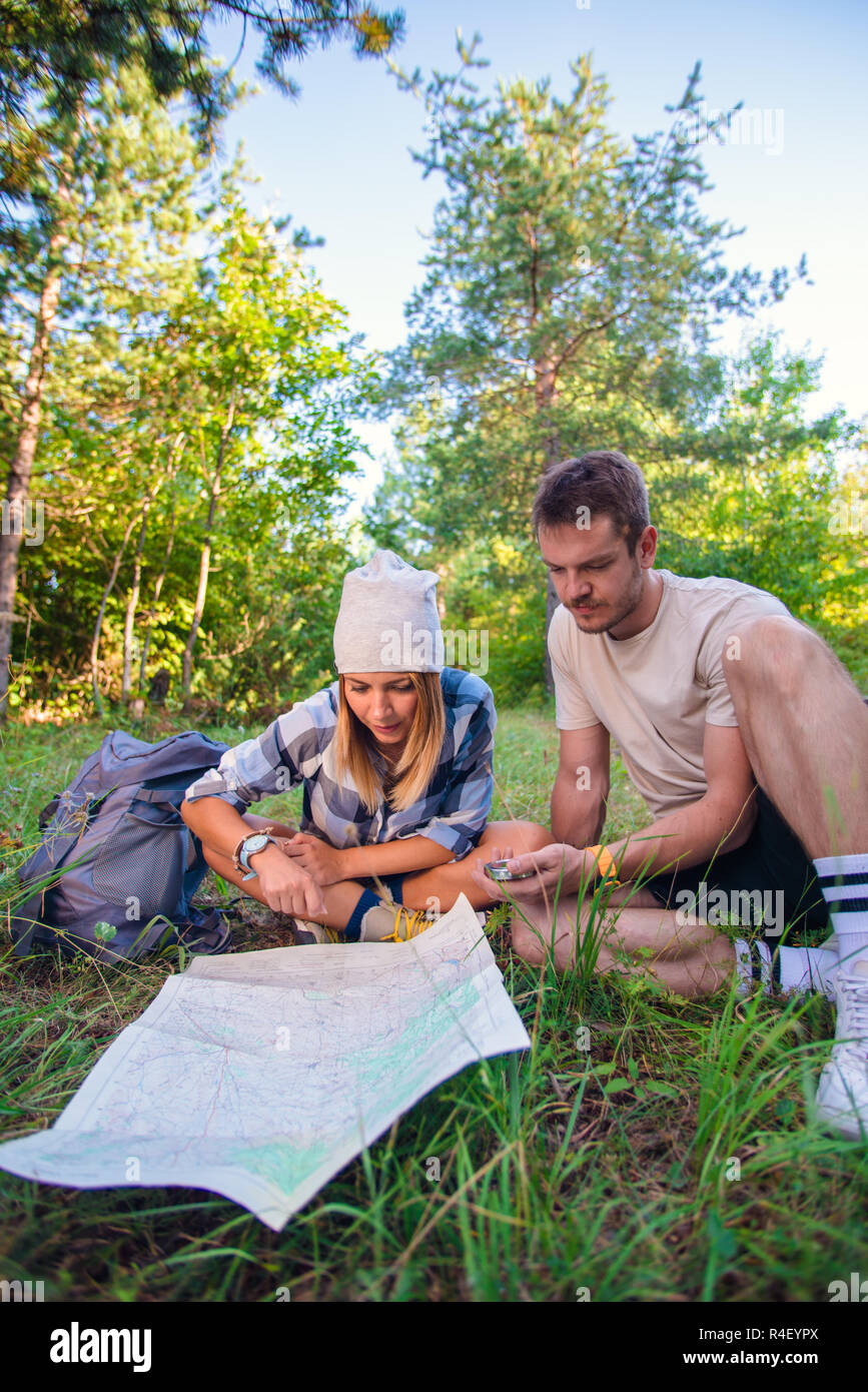 Young couple navigasting using map and compass inside the forest ...
