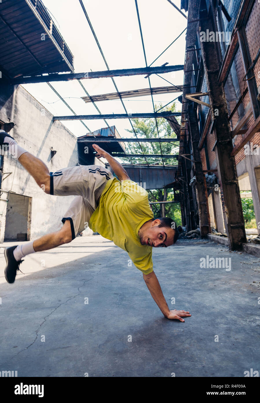 Sporty man maintains a balance on one hand in abandoned place Stock ...