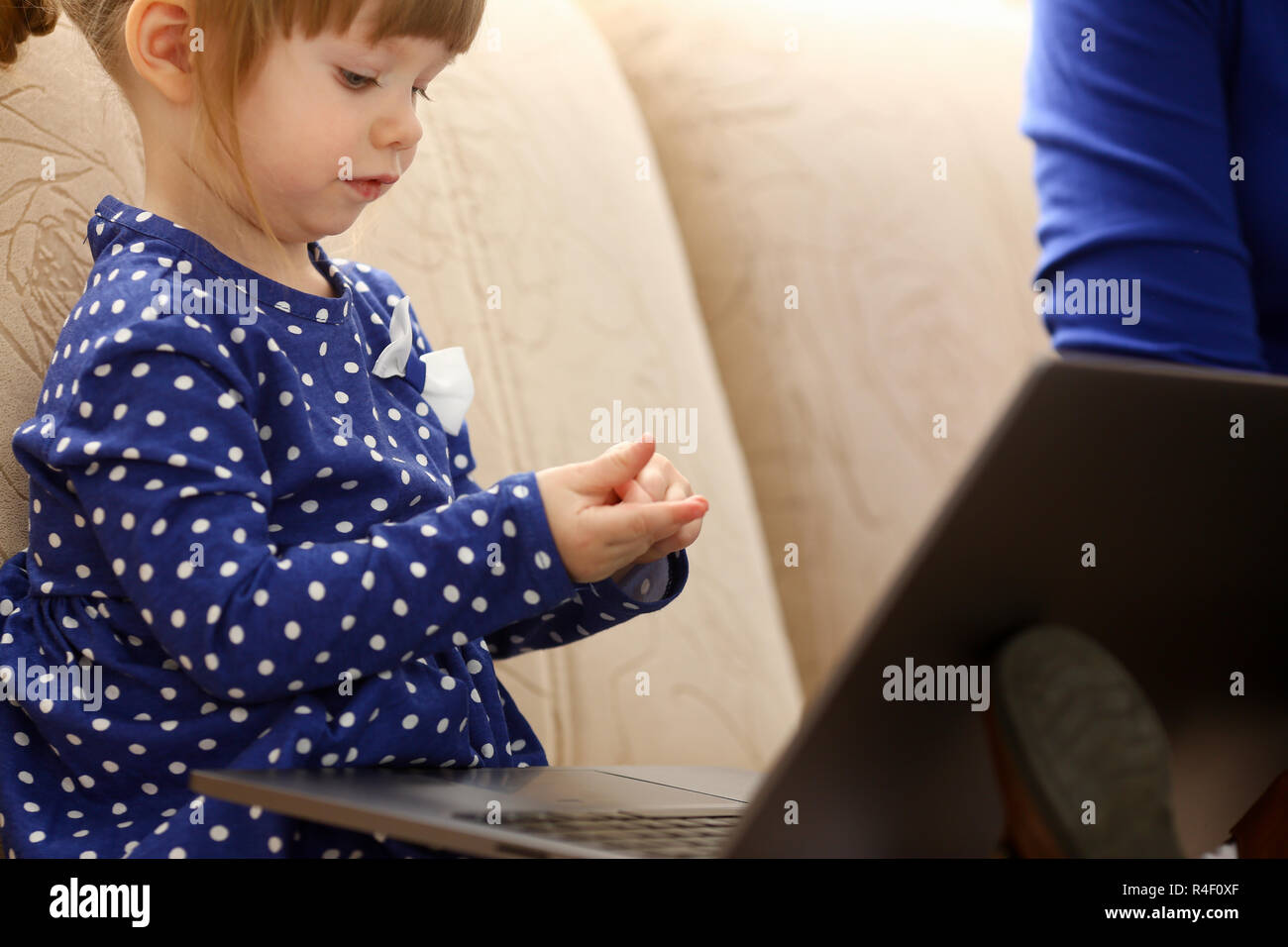 Cute little girl on couch with mom use laptop Stock Photo - Alamy