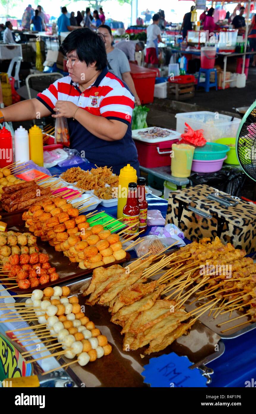 Woman sells fried savory food from stall at outdoor food section Satok ...