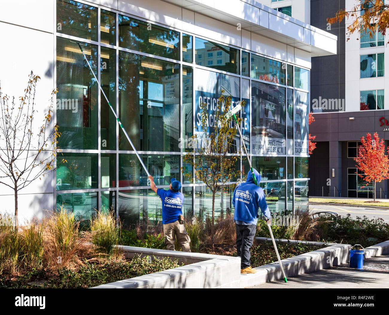 CHARLOTTE, NC, USA-11/21/18: Two men wash windows with attachments on ...