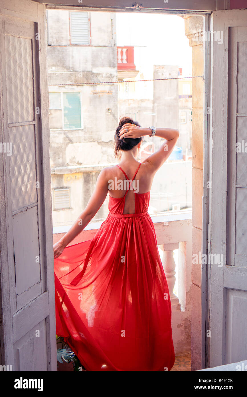 Young attractive woman in red dress on old balcony in apartment in ...