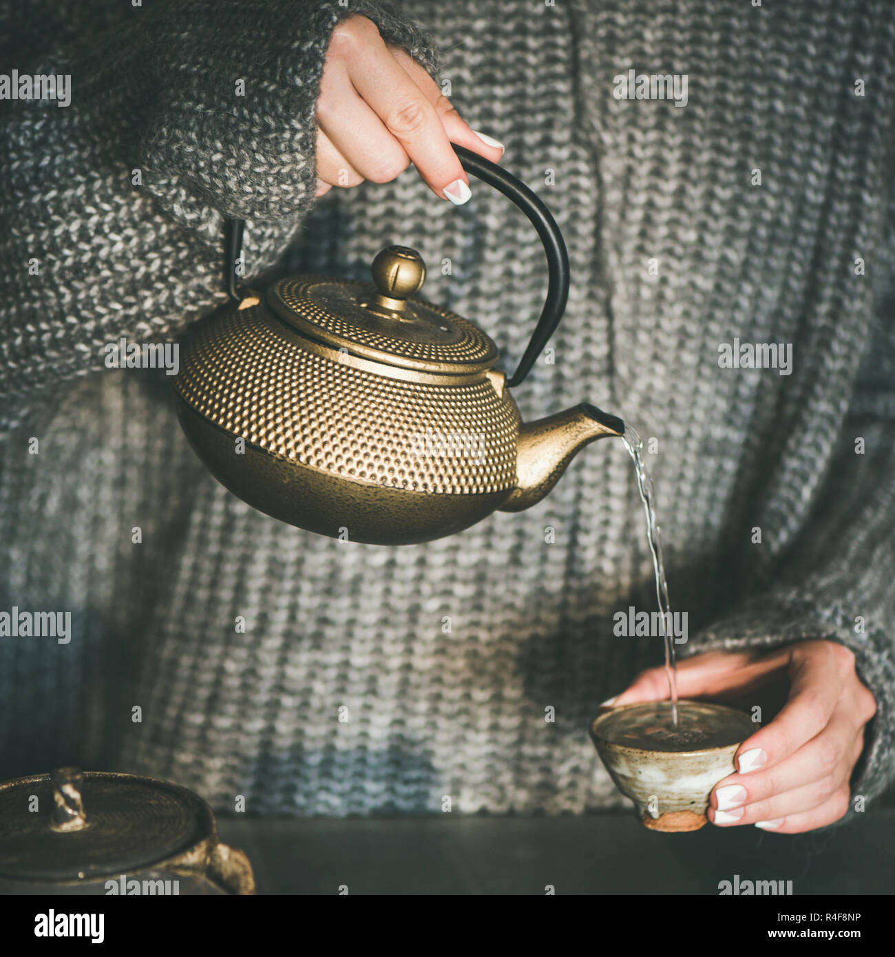 Female pouring green tea from pot into cup, square crop Stock Photo - Alamy