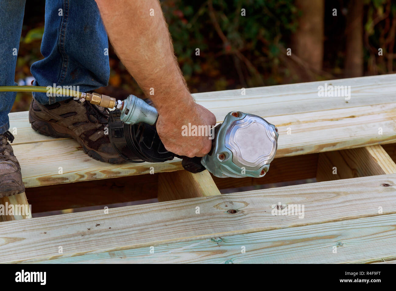 Man building a wooden patio with hammering screwing together beams ...
