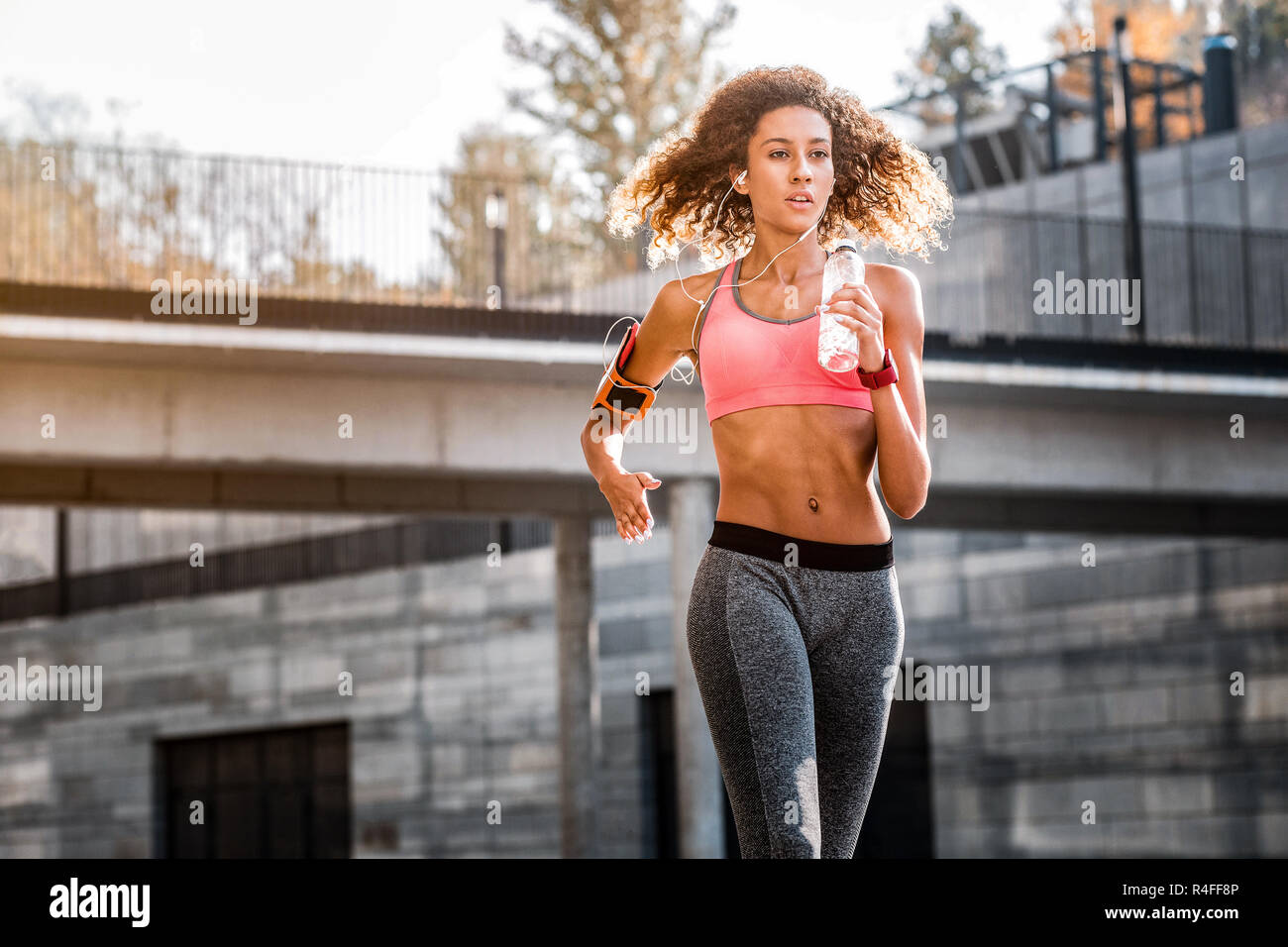 Beautiful fit woman running with a bottle of water Stock Photo - Alamy