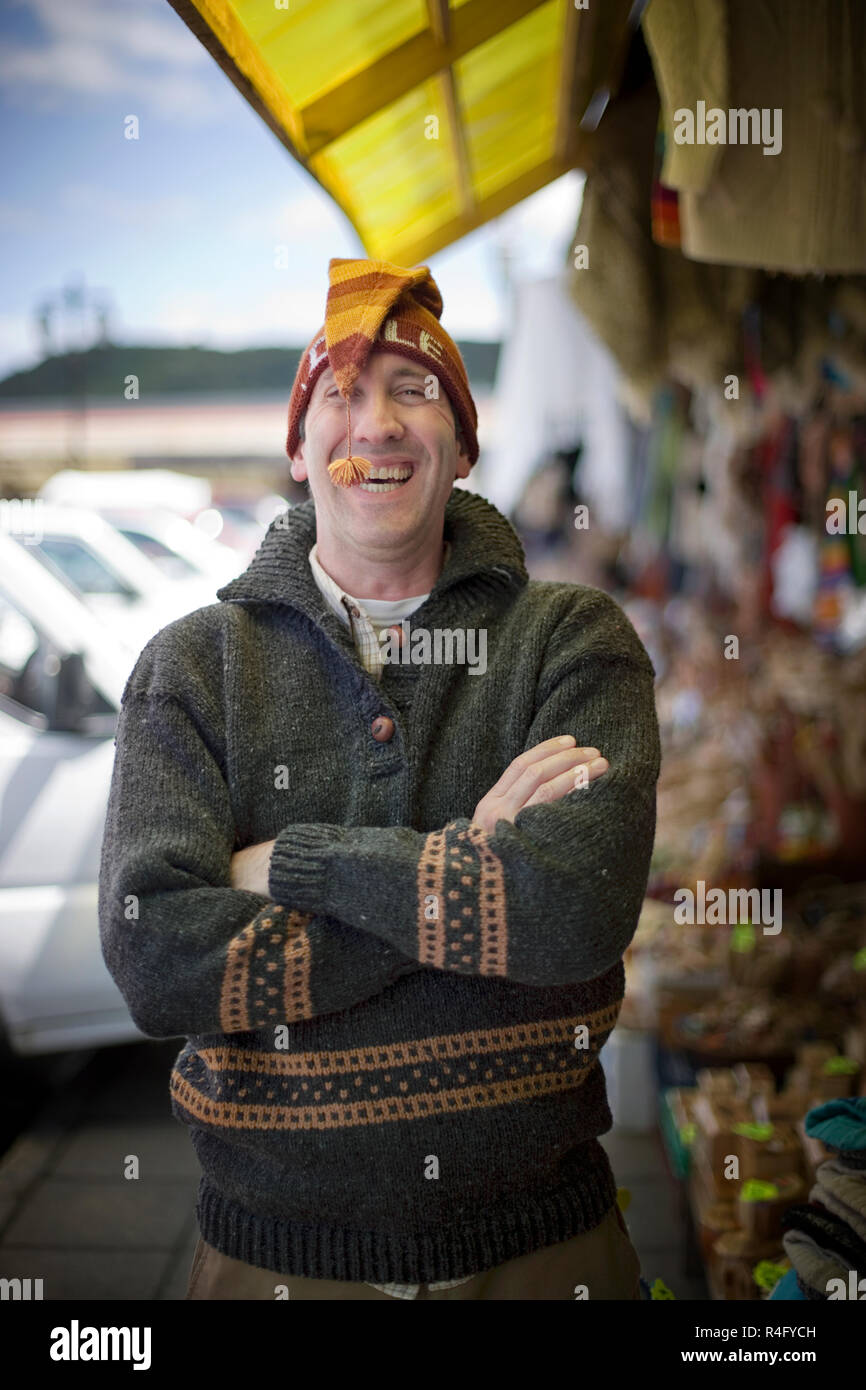 Portrait of a laughing man wearing a silly hat with his arms crossed ...