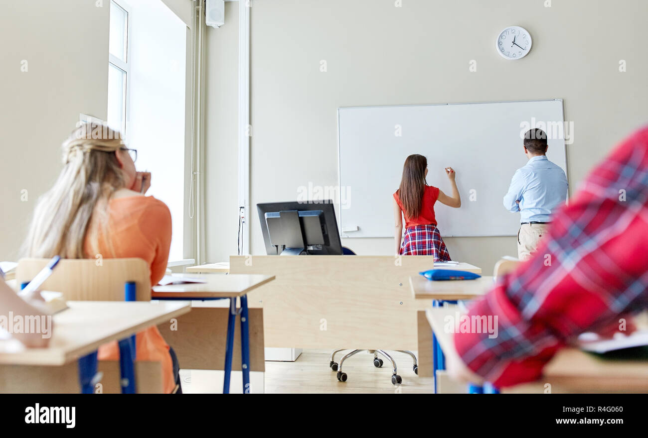 teacher and student writing on board at school Stock Photo - Alamy