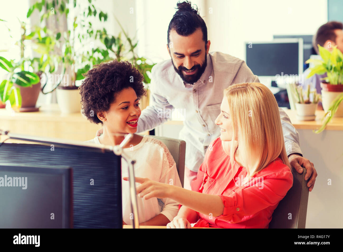 happy creative team with computer in office Stock Photo - Alamy