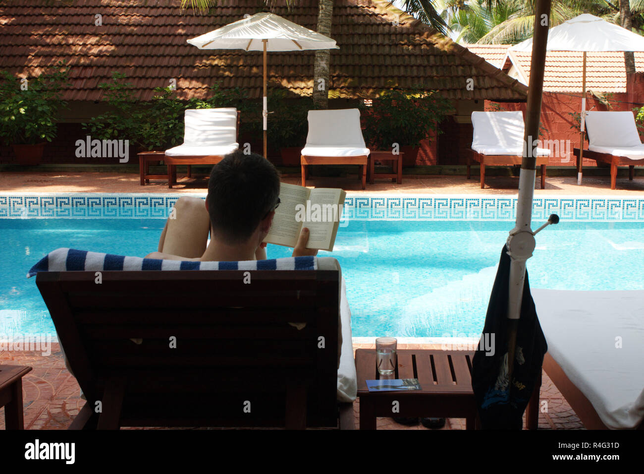 Man reading book at swimming pool Stock Photo - Alamy