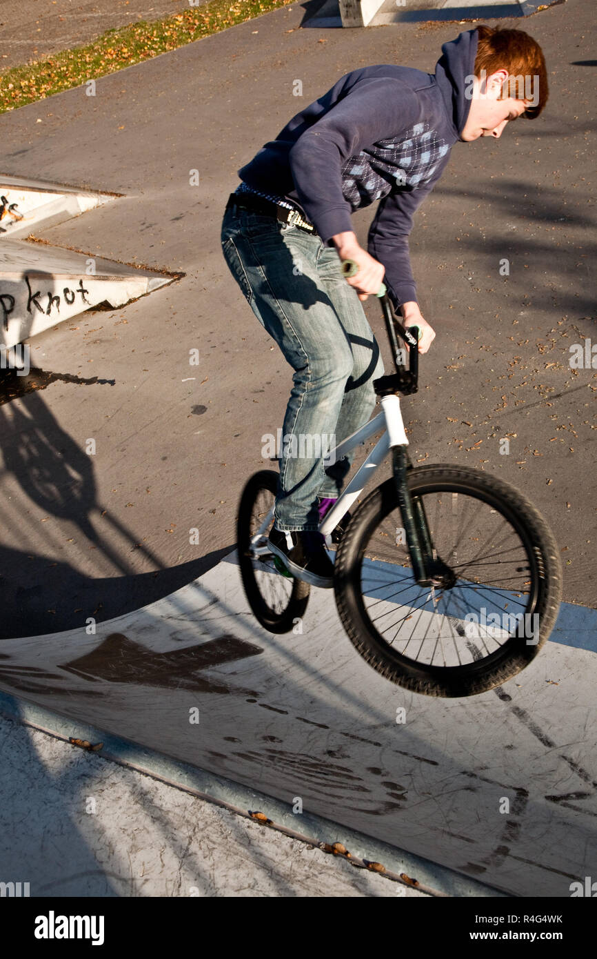 joung red haired boy is jumping with his BMX Bike at the skate park ...