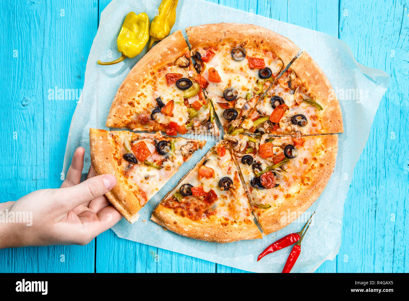 Image of pizza on table. Man take slice Stock Photo - Alamy