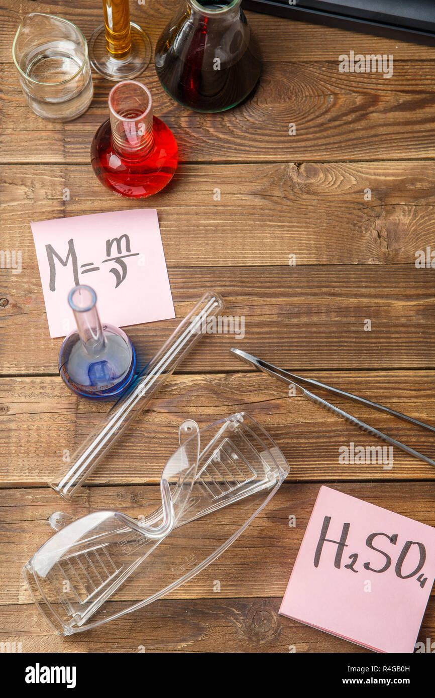 Chemical flasks, tweezers, keyboard, notebooks on a wooden table with ...
