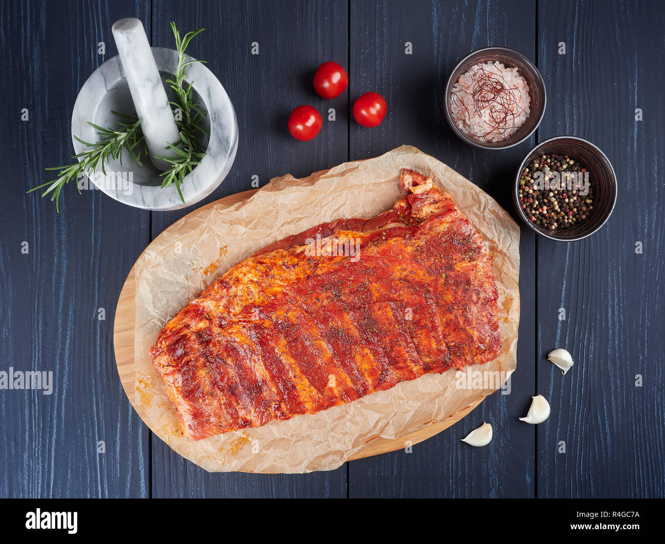 Marinated raw pork spare ribs on crumpled paper on a bamboo cutting ...