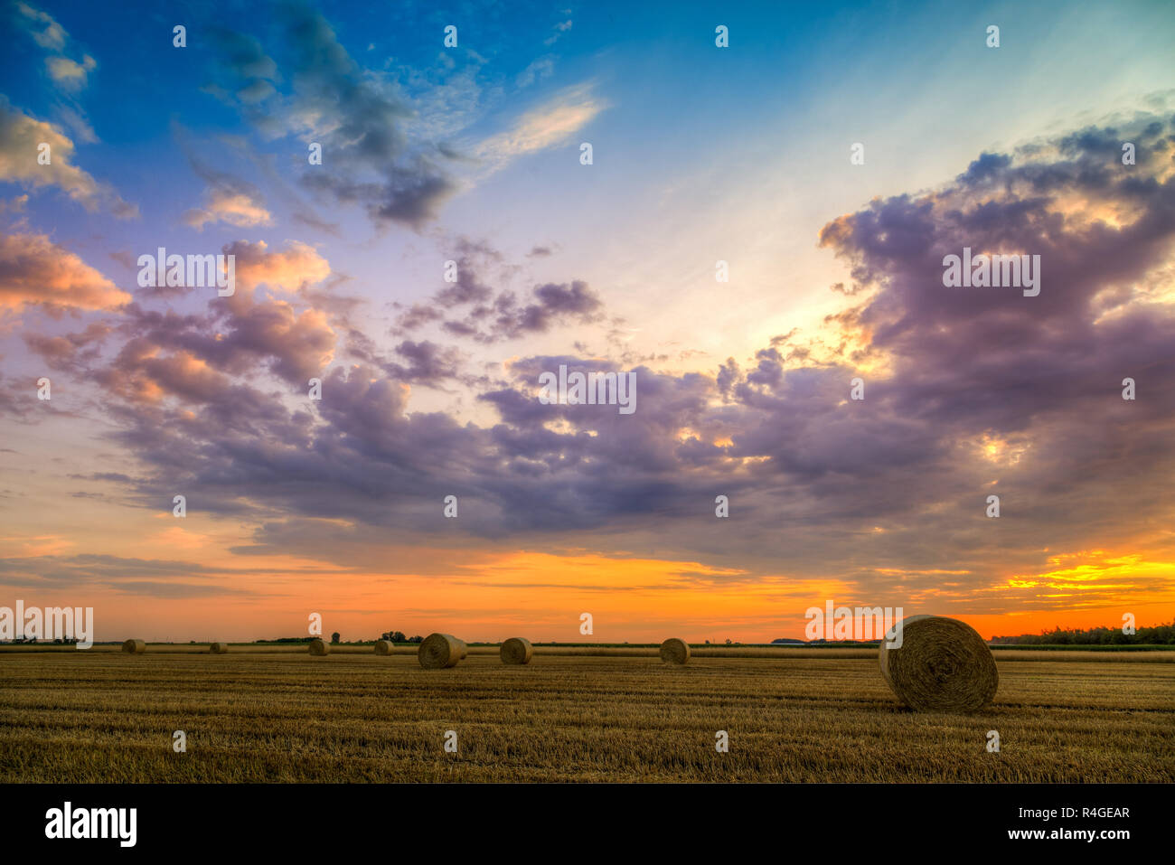Sunset over farm field with hay bales Stock Photo - Alamy