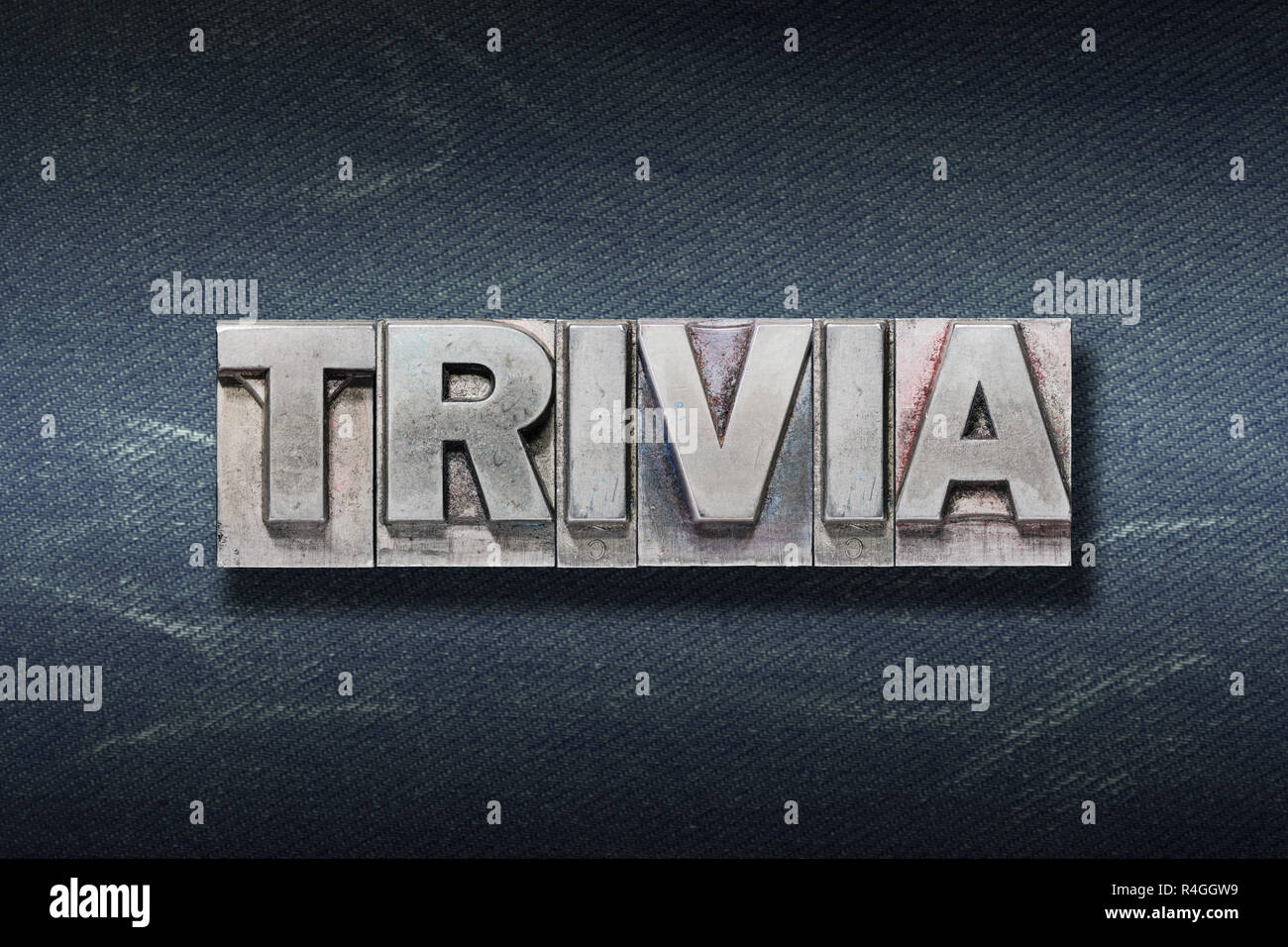 trivia word made from metallic letterpress on dark jeans background ...
