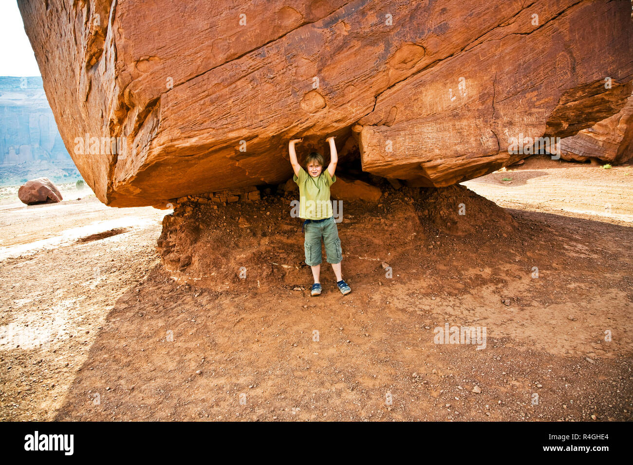 Monument Valley, child has fun by simulatings to carry a big rock Stock ...