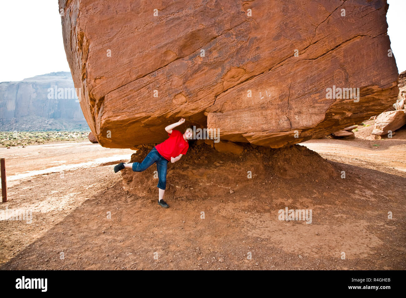 Monument Valley, child has fun by simulatings to carry a big rock Stock ...