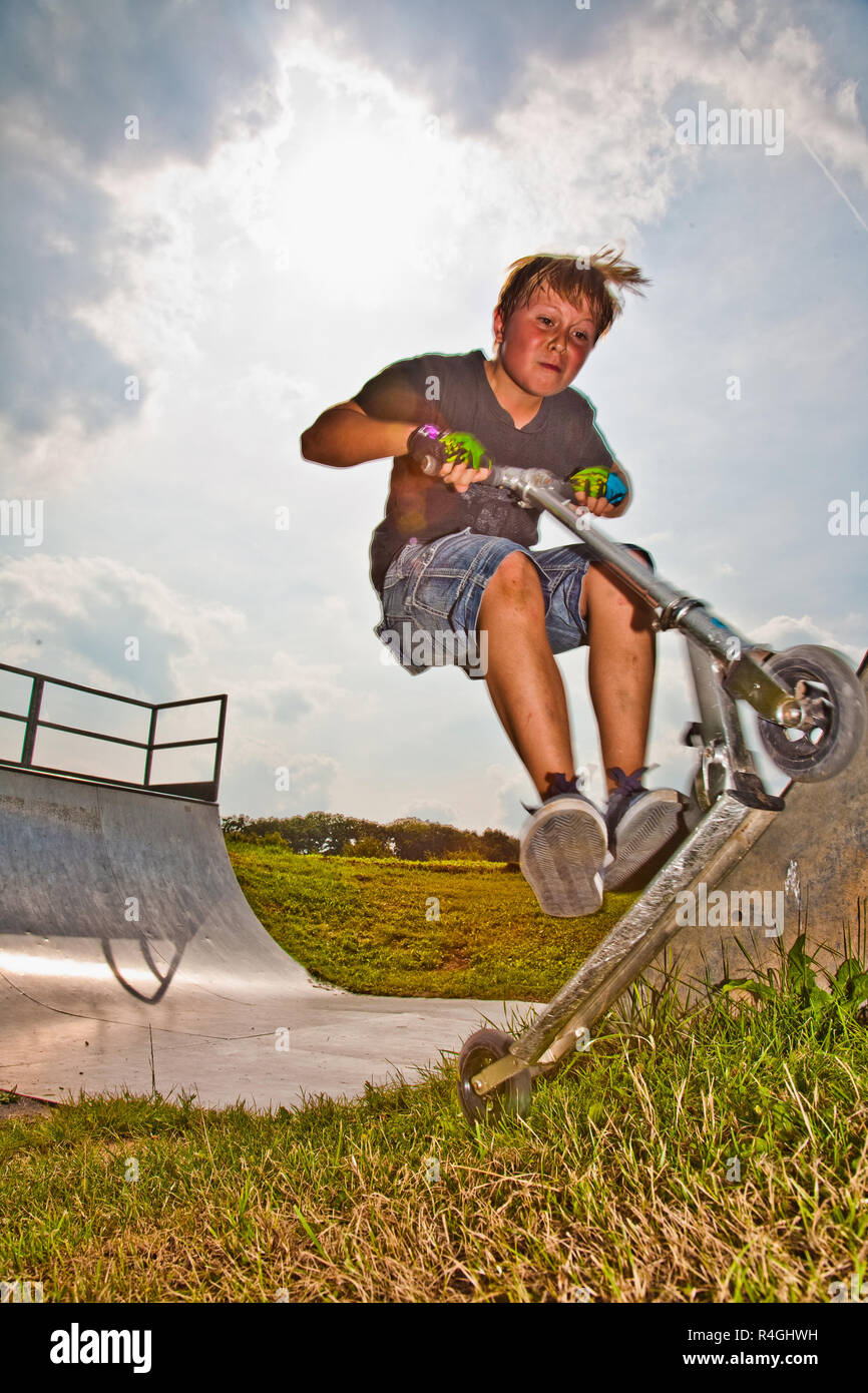 boy is jumping with scooter in pipe Stock Photo - Alamy